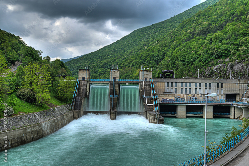 hydroelectric power-plant dam on a river with water overflowing the dam ...