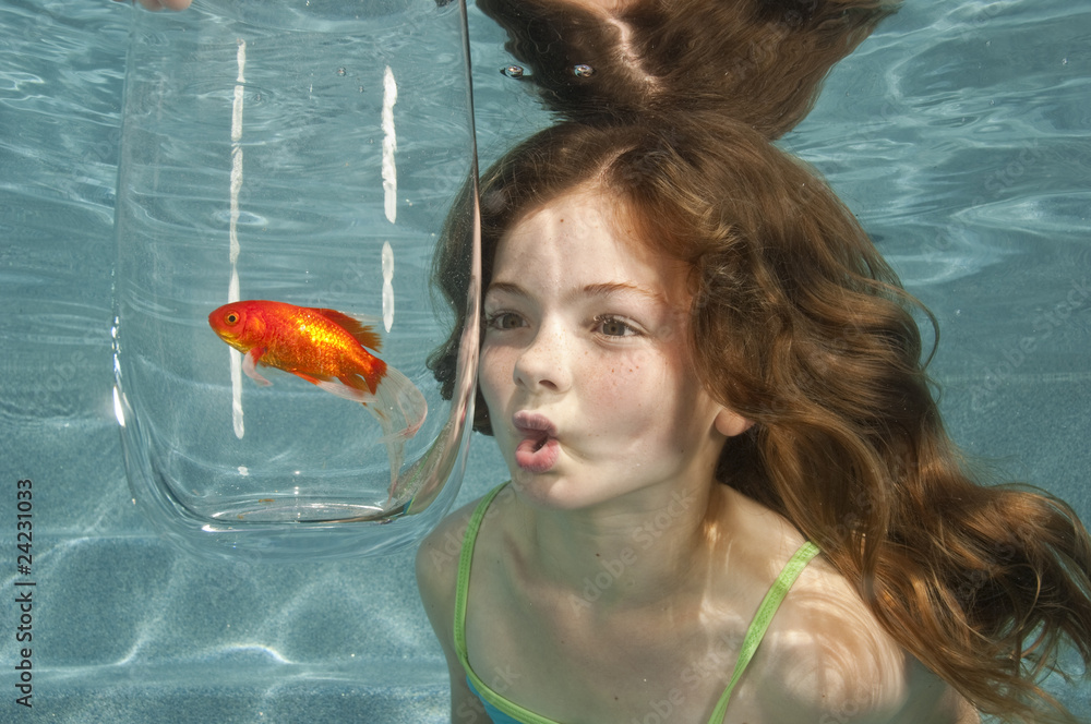 girl making funny fish face swimming underwater with goldfish Stock ...