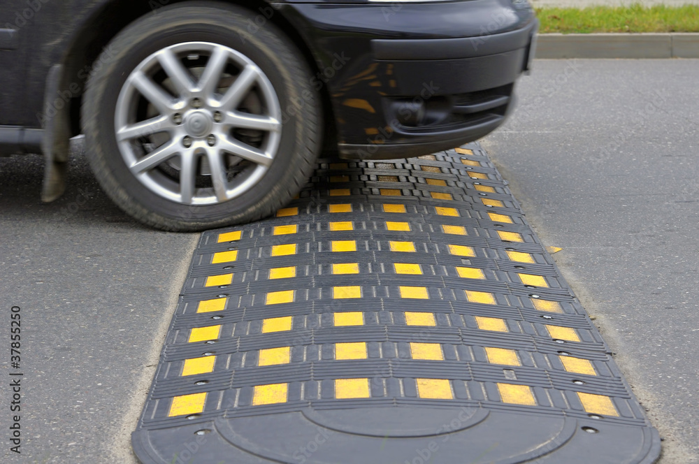 Speed bump on a road when and car Stock Photo | Adobe Stock