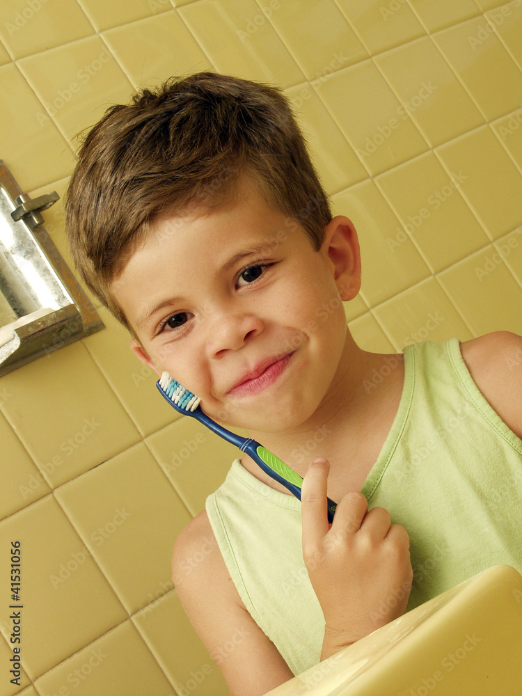 Niño cepillándose los dientes en un baño. Stock Photo | Adobe Stock