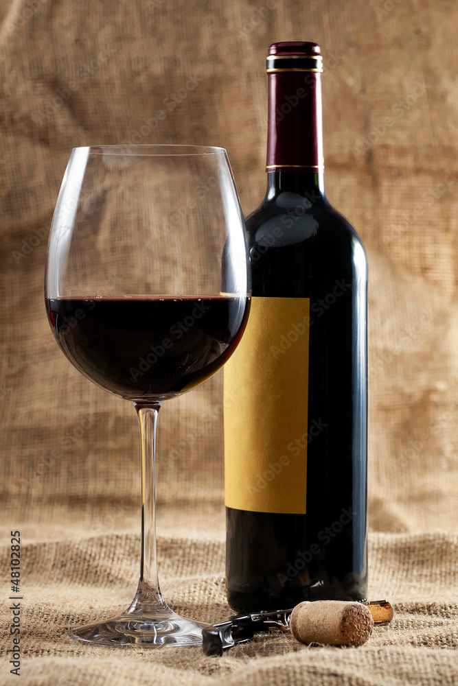 Foto de Stock Botella de vino tinto y copa llena | Adobe Stock