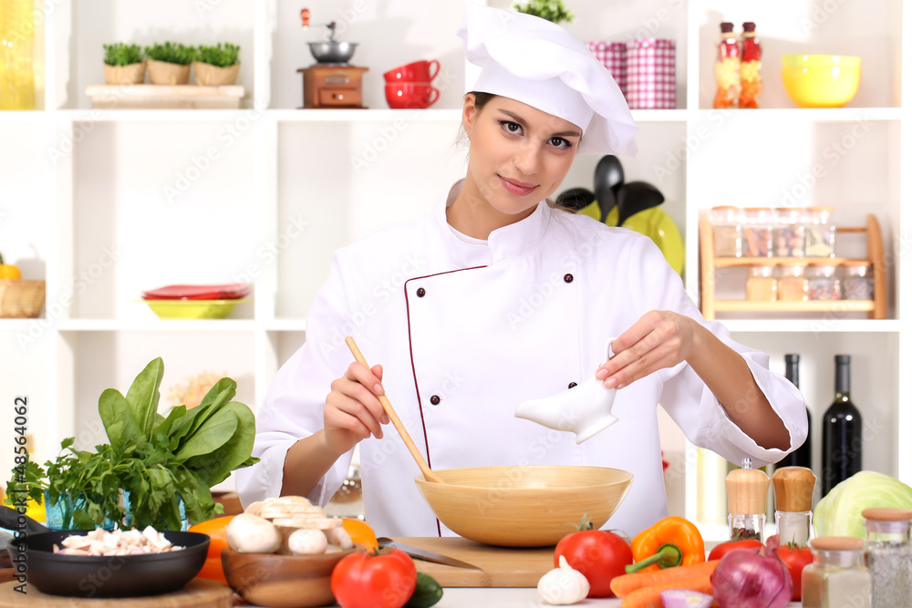 Young woman chef cooking in kitchen Stock Photo | Adobe Stock