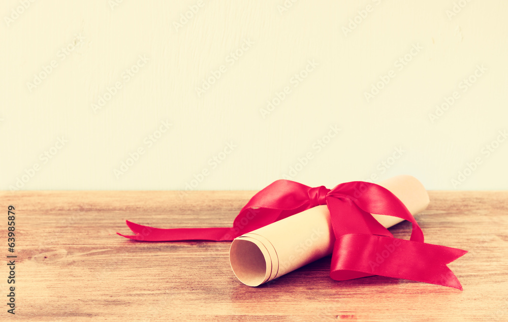 diploma scroll and red ribbon over wooden shelf Stock Photo | Adobe Stock