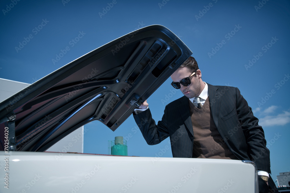 Retro fifties mafia fashion man looking in trunk of vintage car. Stock ...