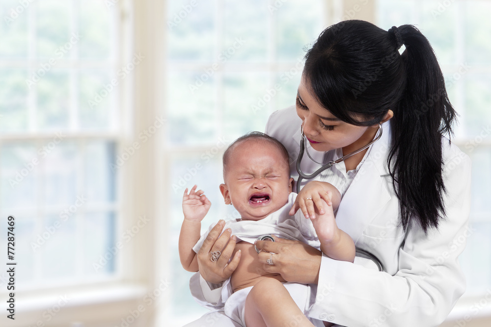 Baby girl crying when examined by doctor Stock Photo | Adobe Stock