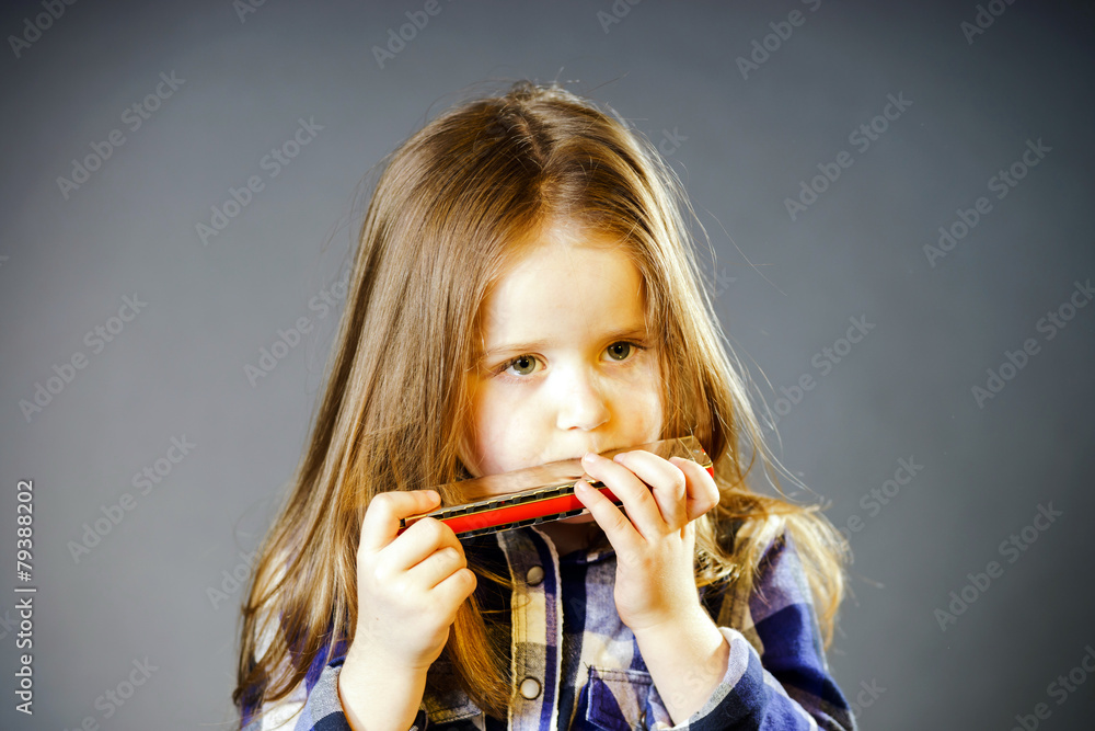 Cute little girl playing harmonica Stock Photo | Adobe Stock