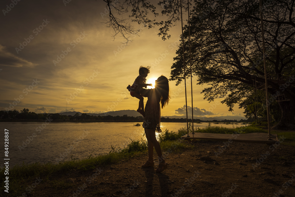Mother and daughter playing at river side. Throwing up daughter in the ...