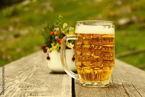 halbe bier mit blumen auf alm I foto Stock | Adobe Stock