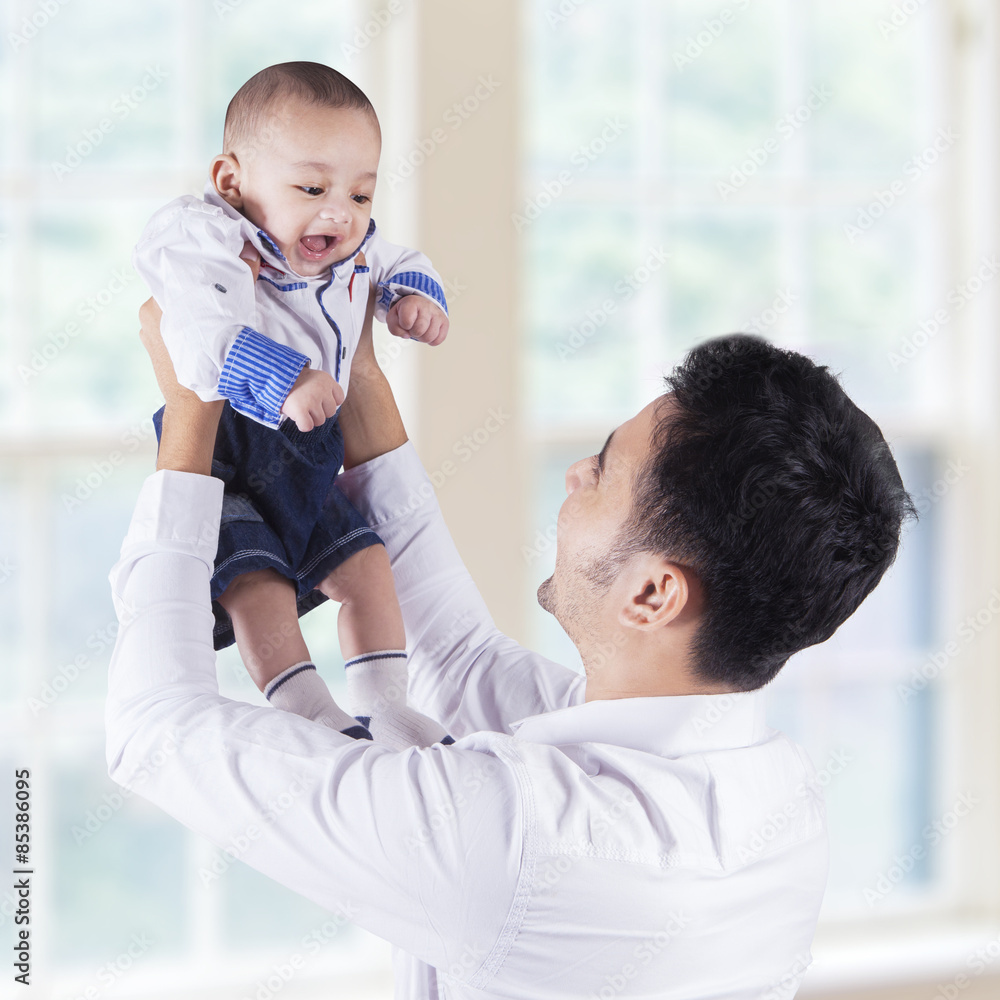 Happy father lift up his baby near the window Stock Photo | Adobe Stock
