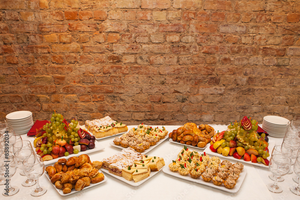 Festive well-laid table with food and drink on brick wall background ...
