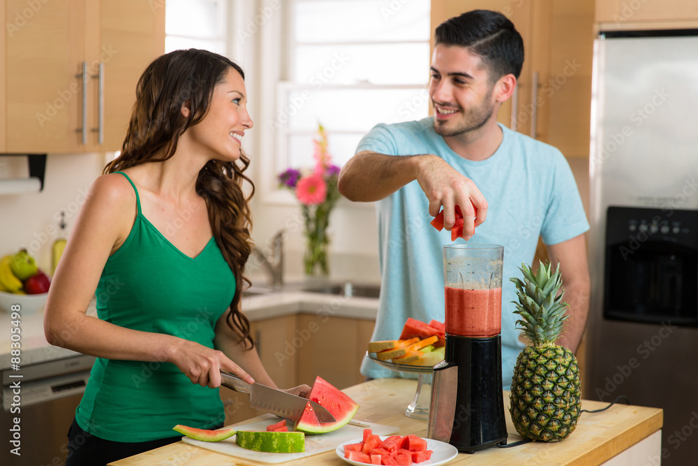 Handsome man and pretty woman chop fresh fruits and veggies smoothie ...