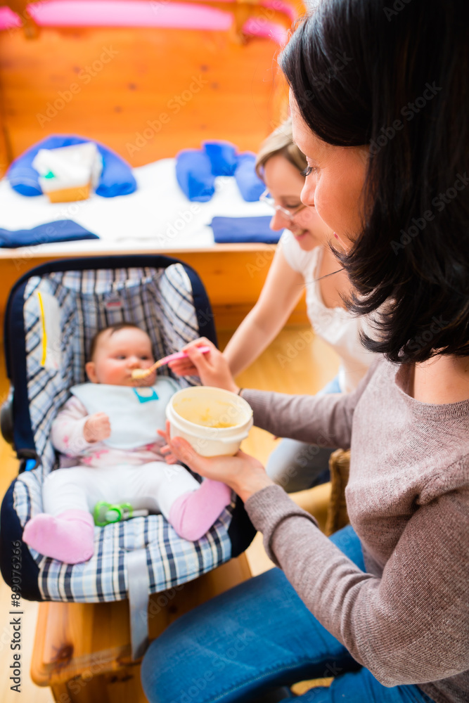 Stock-Foto „Mutter füttert Baby bei Hebamme“ | Adobe Stock