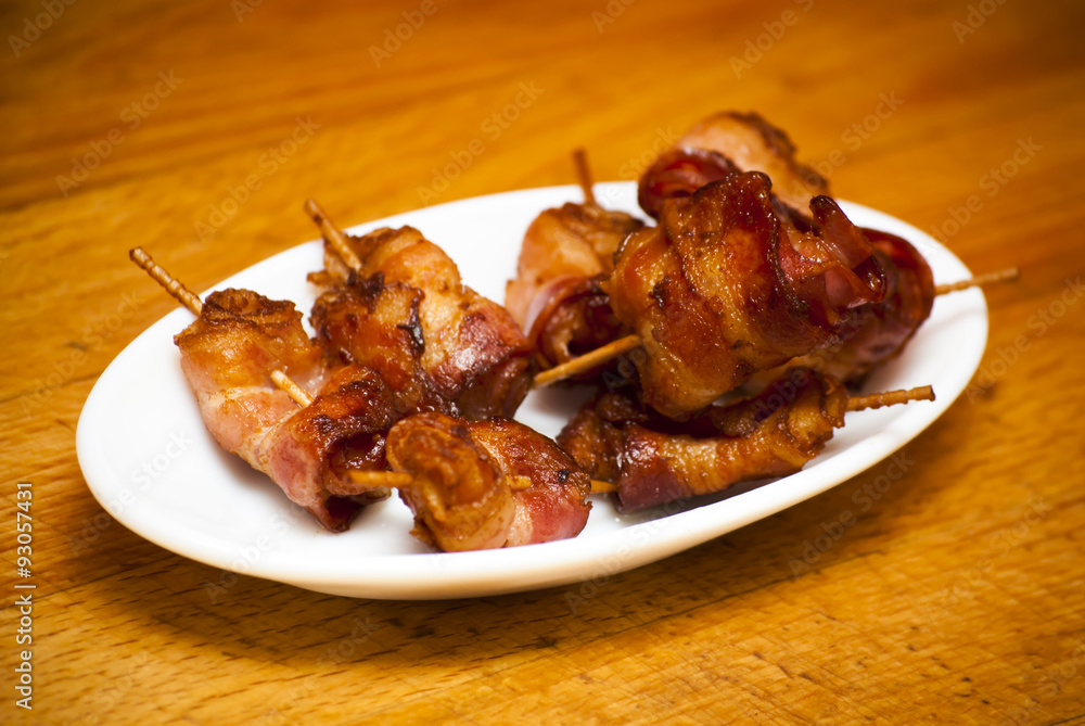 Rolls of slices of cooked bacon subject with a toothpick on a wh Stock ...