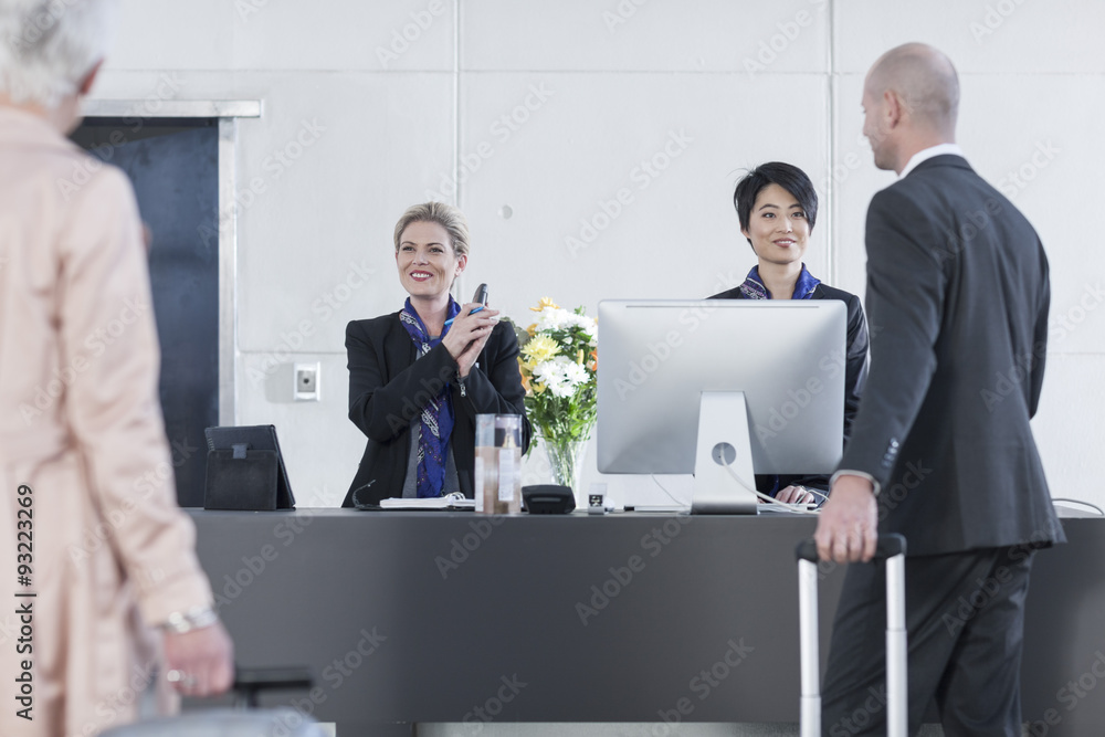 Two women behind reception desk in hotel lobby helping guests Stock ...