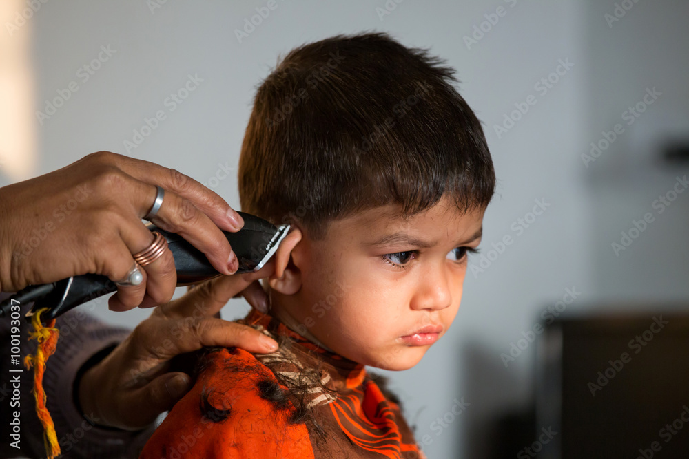 two year old kid having a haircut with wet eyes after crying early ...