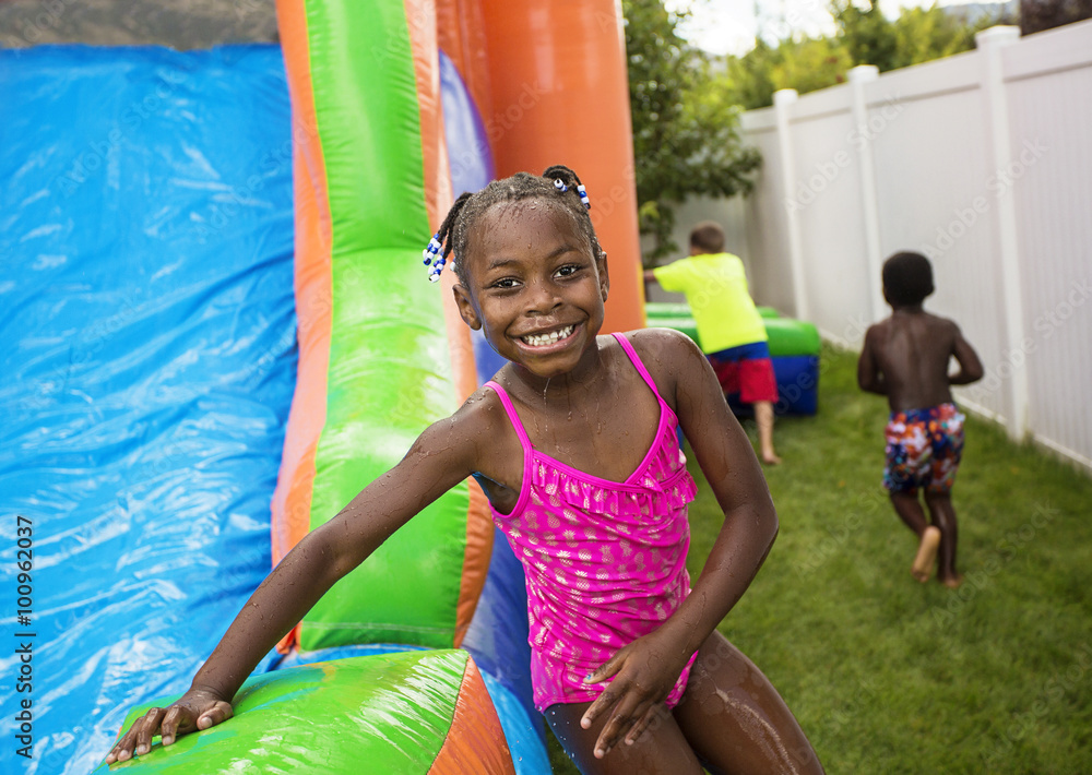 Smiling Little Girl Playing Outdoors On An Inflatable Bounce House