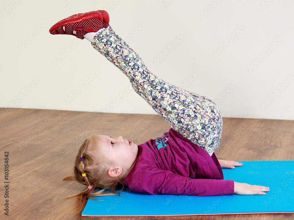 Little girl is doing leg lifting workout on a mat Stock Photo | Adobe Stock