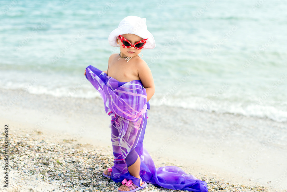 The child, a little girl posing on the beach, small model on the beach ...