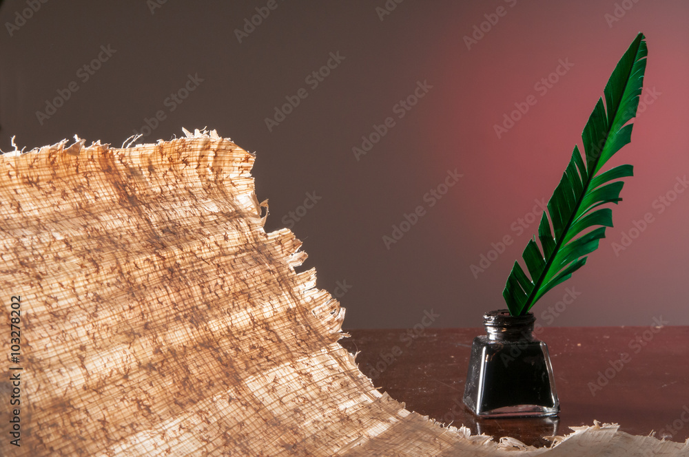 Green quill pen and a backlit papyrus sheet with its particular texture ...