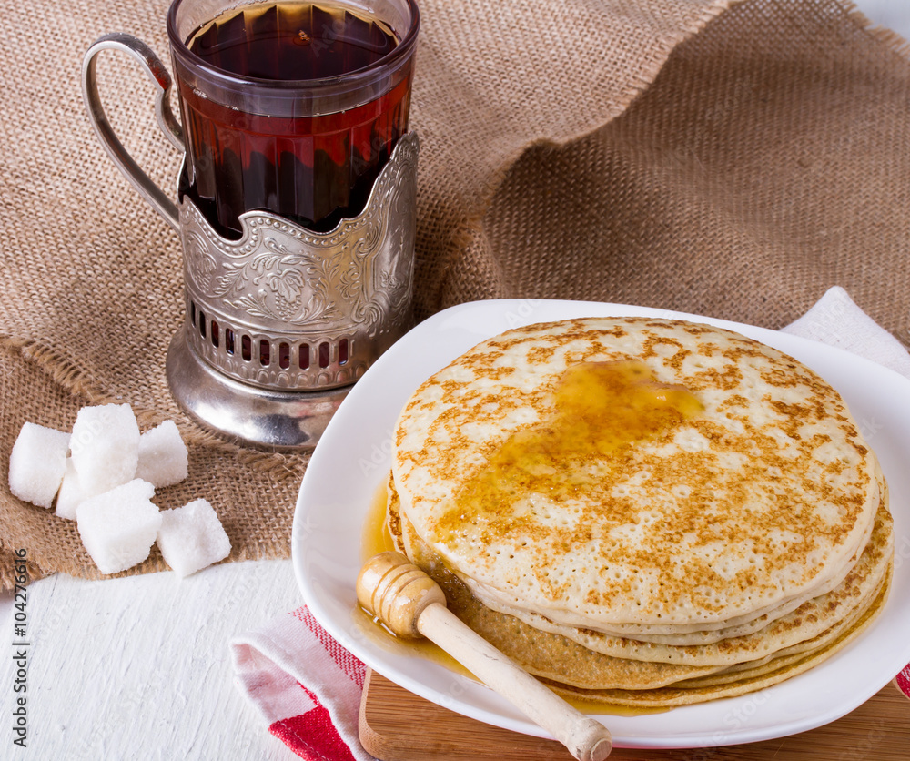 Pancakes with honey and a glass in the old cup holder with a tea Stock ...