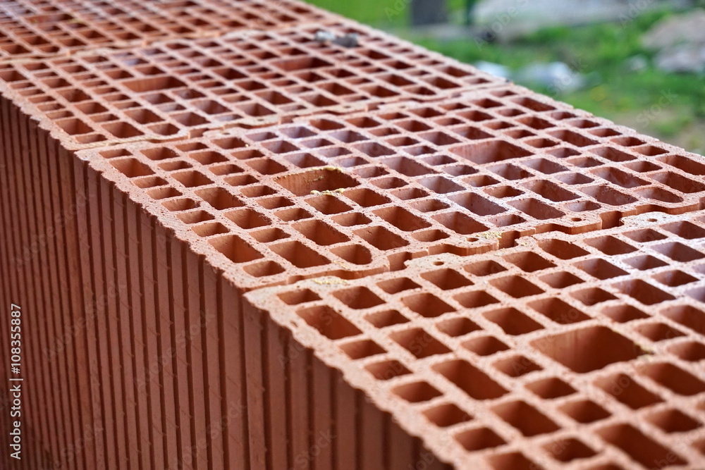 Row of red bricks with the inner holes in the shape of honeycomb on the ...