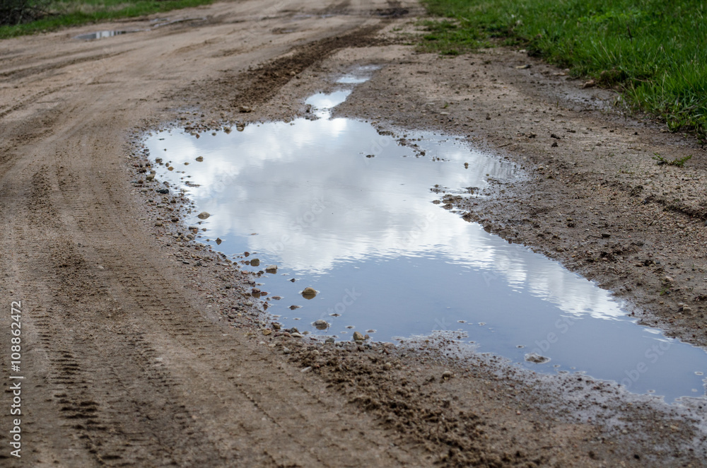 Dirty road and grass with puddles and cloud reflection / reflection of ...