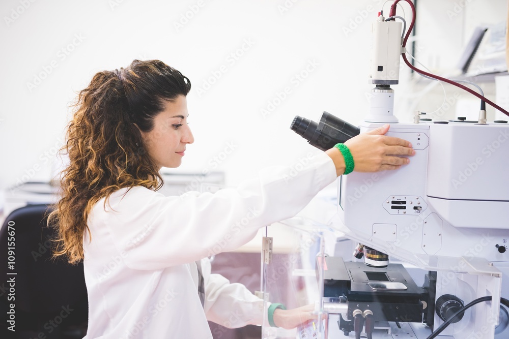 Female scientist using FTIR spectrophotometer, focusing sample on ...