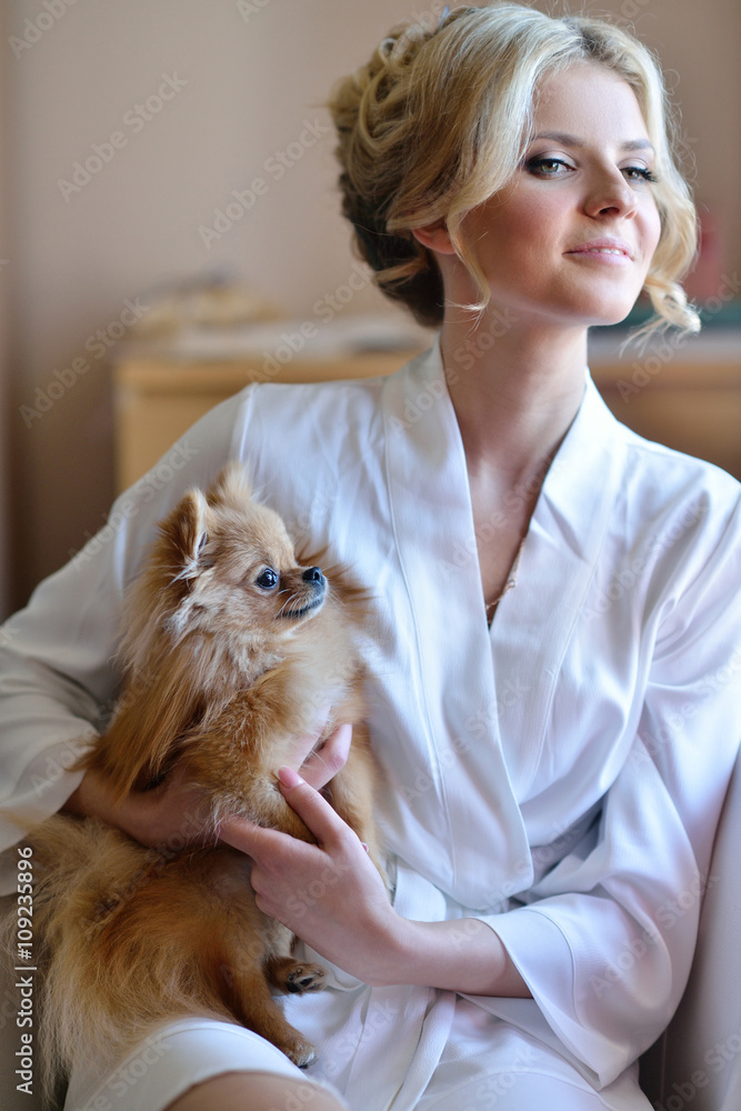 Beauty bride in dressing gown with a cute dog indoors. Beautiful model ...
