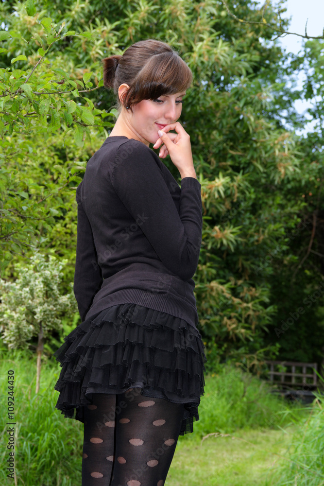 Jugendliche mit Minirock und schicker Strumpfhose steht sinniernd im ...