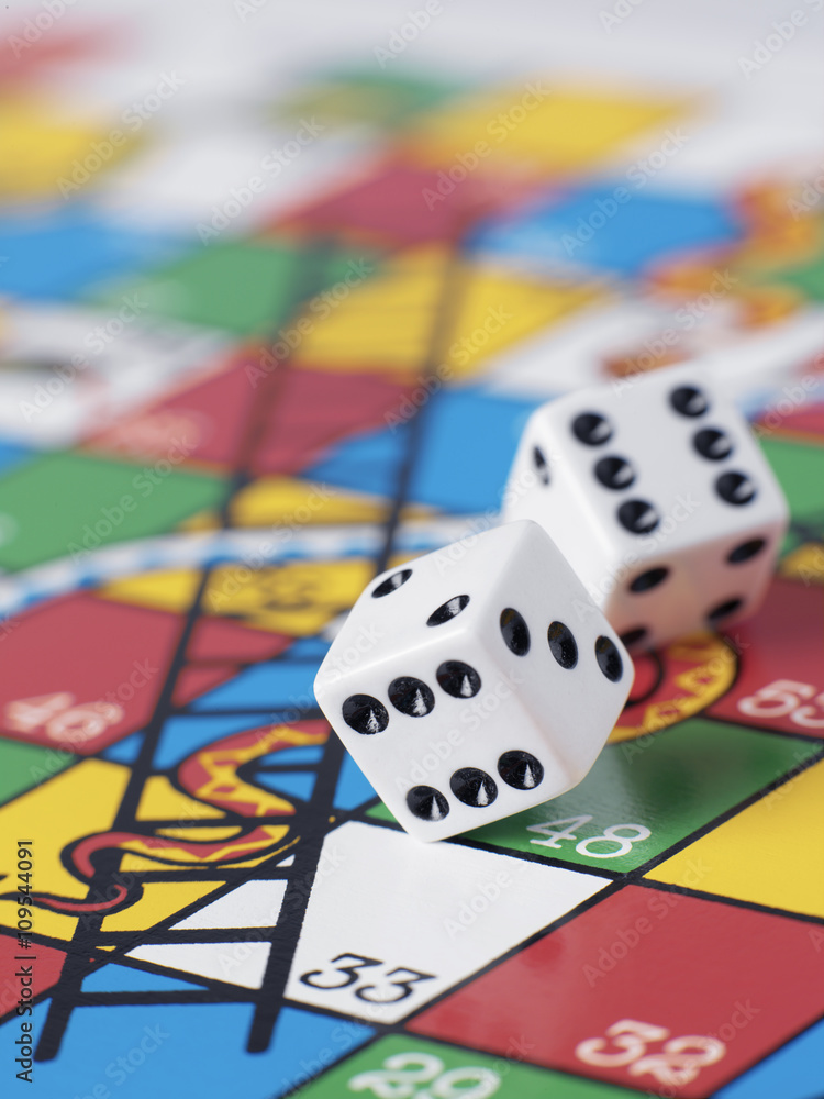 Dice falling onto snakes and ladders board Stock Photo | Adobe Stock