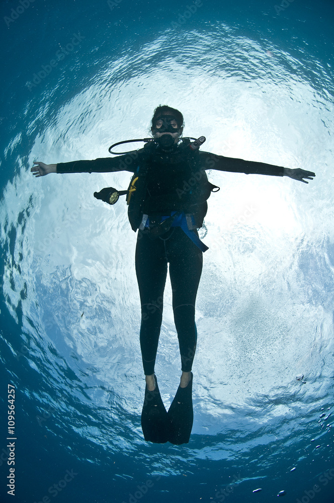 Full length front view of scuba diver arms open floating near water ...