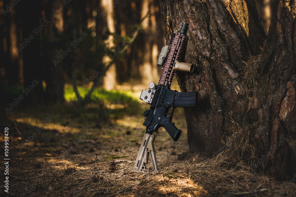 assault rifle leaning on a tree in the forest Stock Photo | Adobe Stock