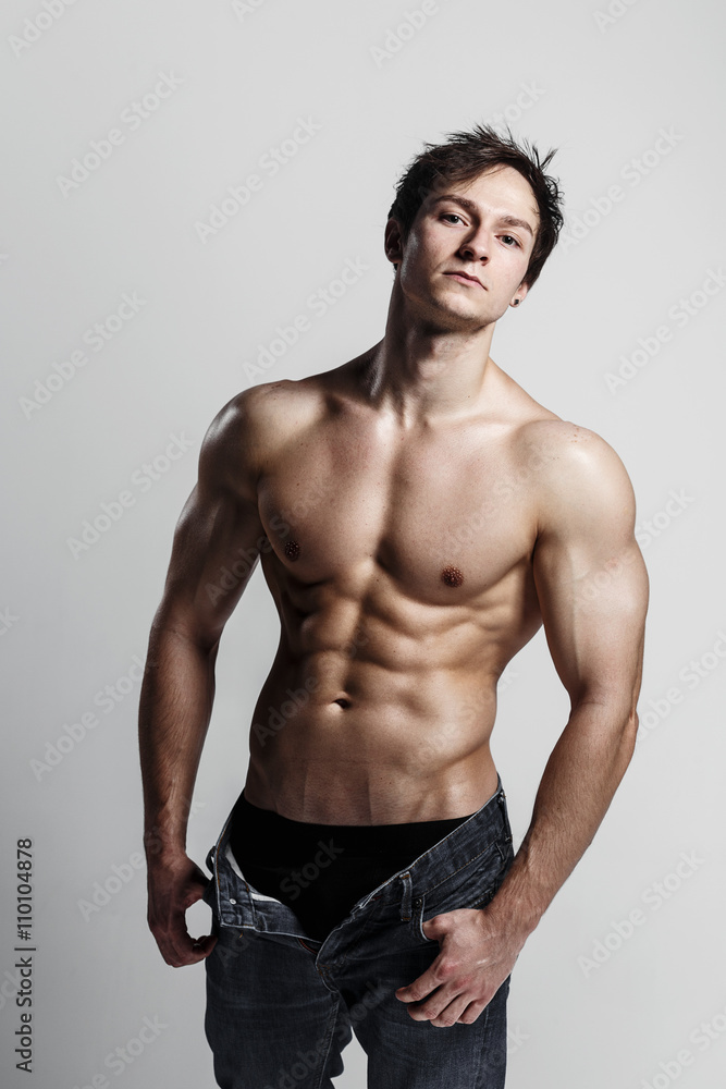 Muscular male model bodybuilder with unbuttoned jeans. Studio shot on ...
