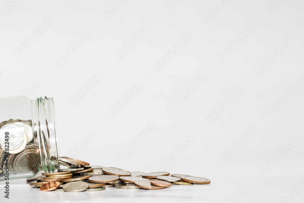 Coins spilled from glass jar, with copy space on white background Stock ...