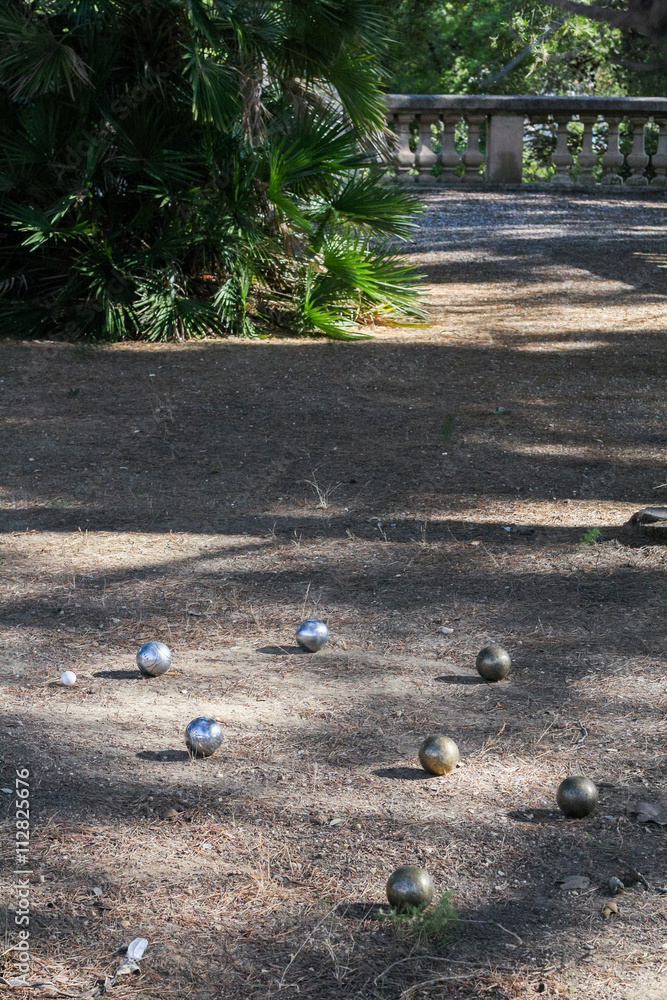 Steel balls for a game of boules on the ground among light and shadow ...