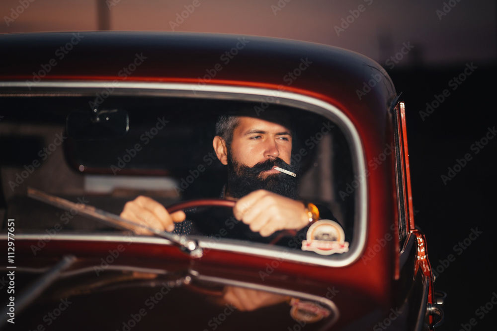 brutal bearded man with a smart mustache brunette sitting in a dark ...