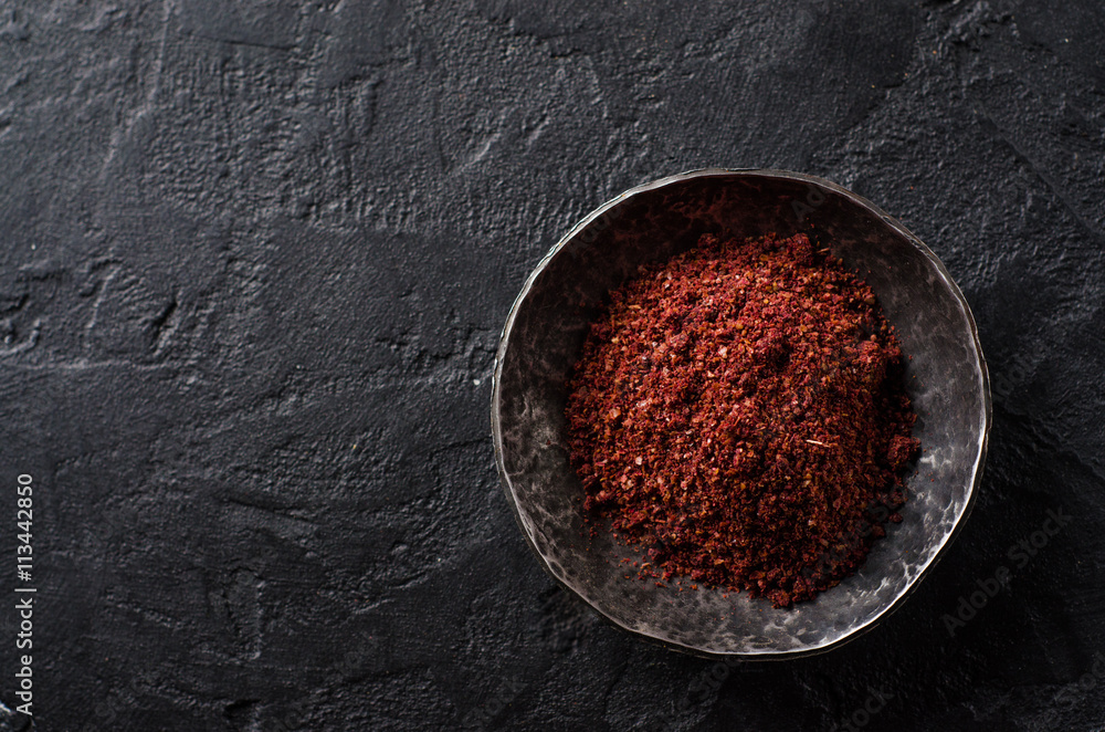 sumah or sumak - east spice in metal bowl on dark background. Selective ...