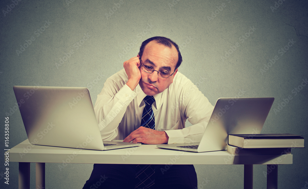 Bored business man sitting in front of two laptop computers Stock Photo ...