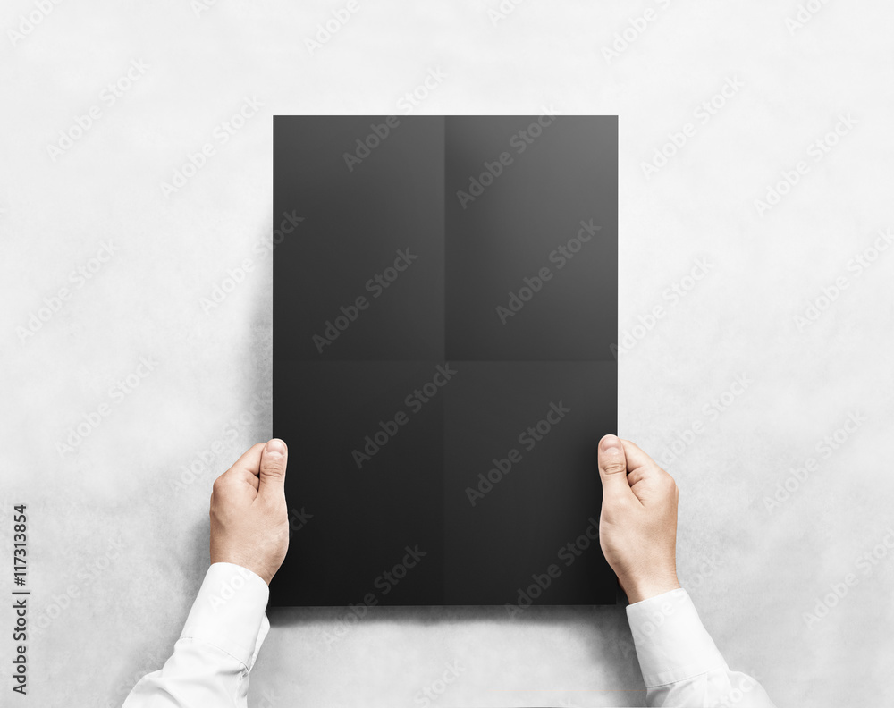 Hand holding black folded blank poster mockup, isolated. Arm in shirt ...