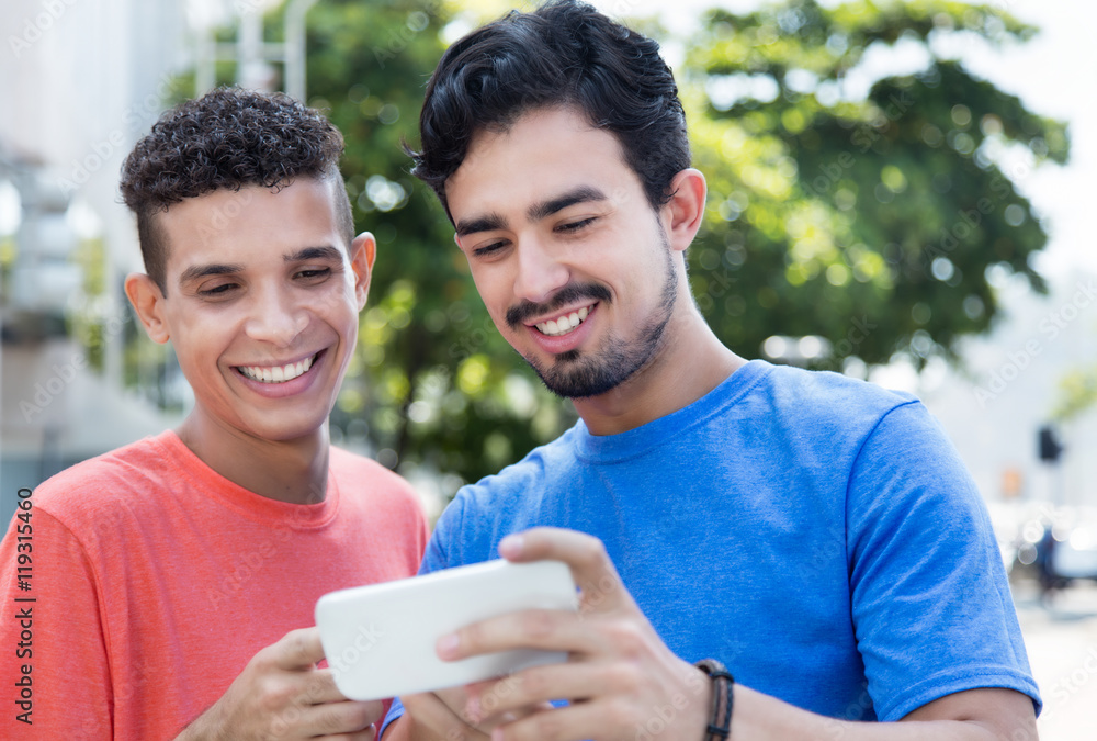 Two hispanic guys showing pictures on phone Stock Photo | Adobe Stock