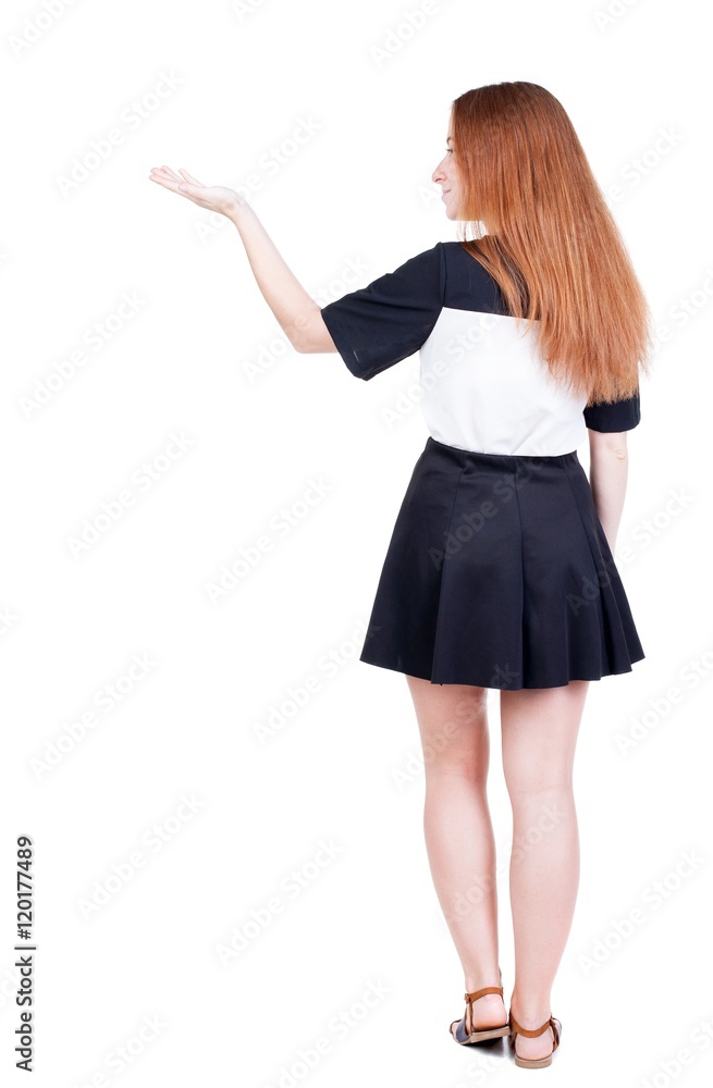 Back view of Beautiful woman in dress looking at wall and Holds hand up ...