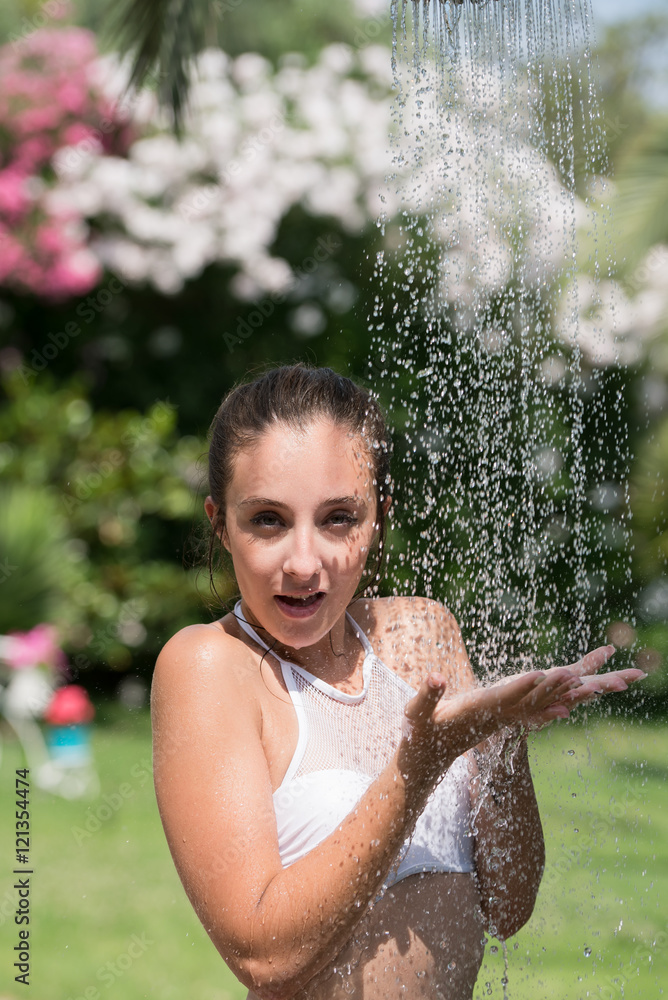 Girl wear bikini standing under the outdoor pool shower. Playful time ...