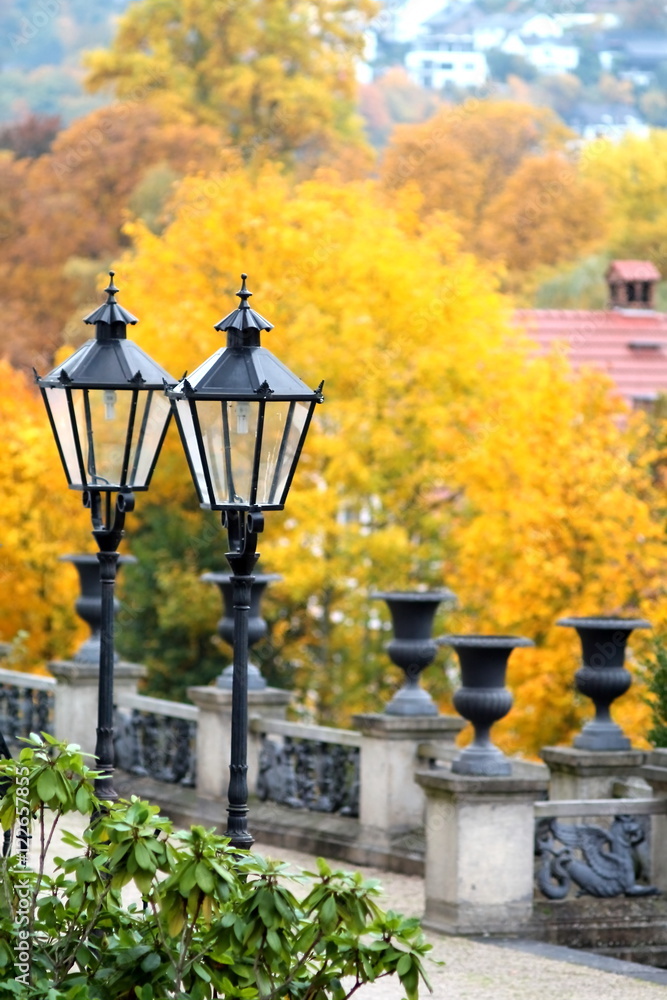 Fall scene with two old street lights , bronze vases and yellow trees ...