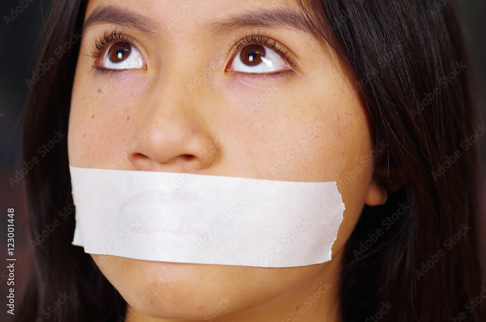 Young brunette woman tied up with rope around wrists and white tape ...