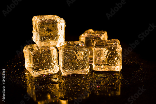 Ice cubes of gold color on a reflective surface. Stock Photo | Adobe Stock