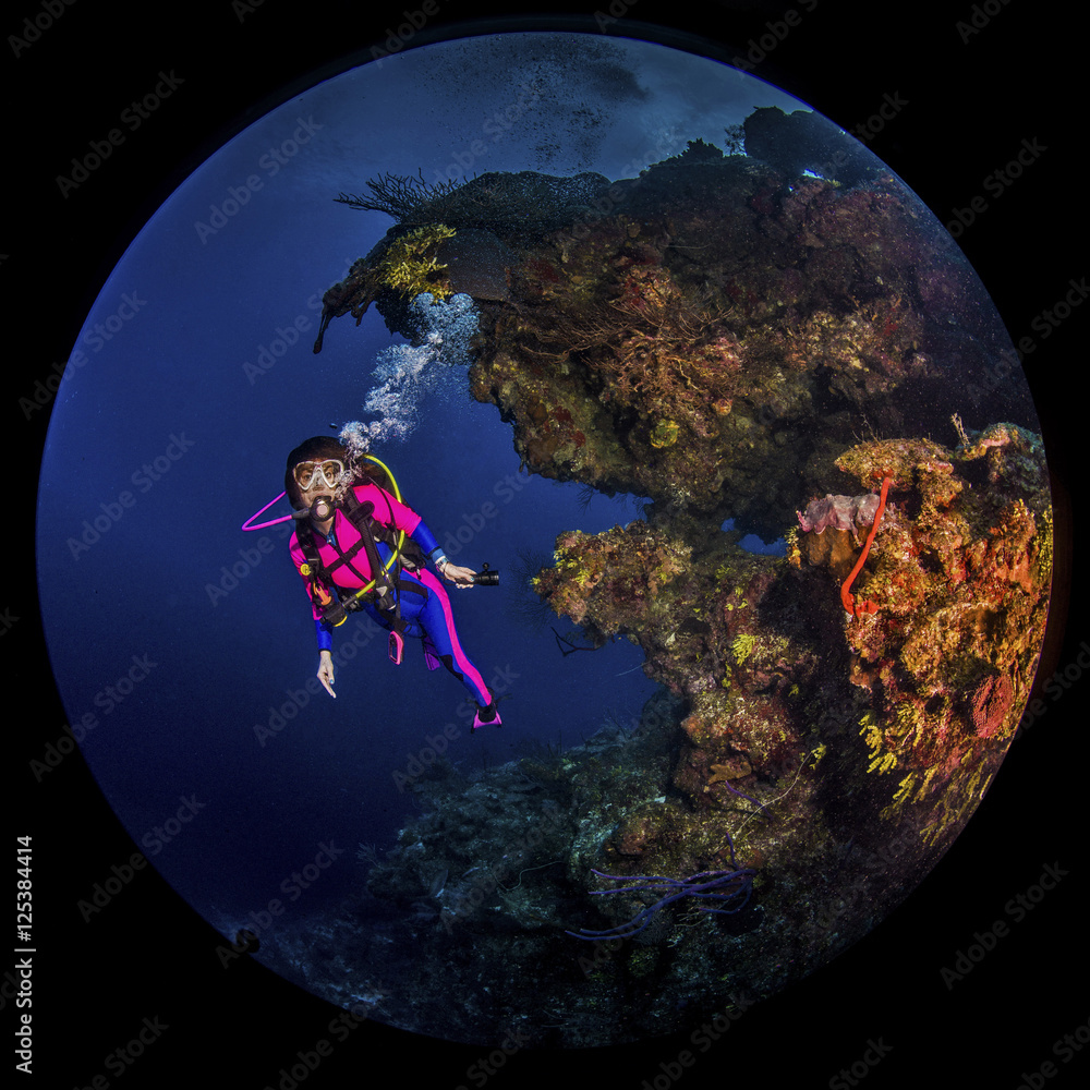 A circular fisheye image of a female SCUBA Diver exploring a Caribbean ...