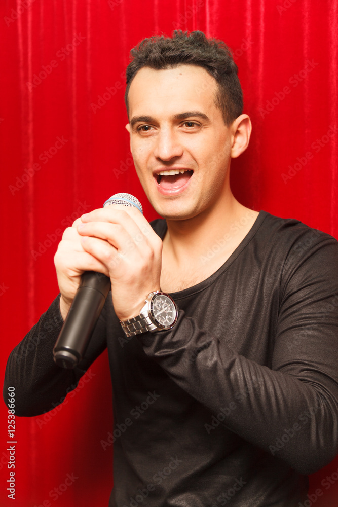 young man singing with a microphone on a red background Stock Photo ...