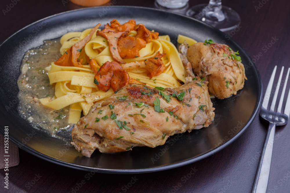 Tagliatelle with chanterelles and stewed rabbit on black terelke. side ...