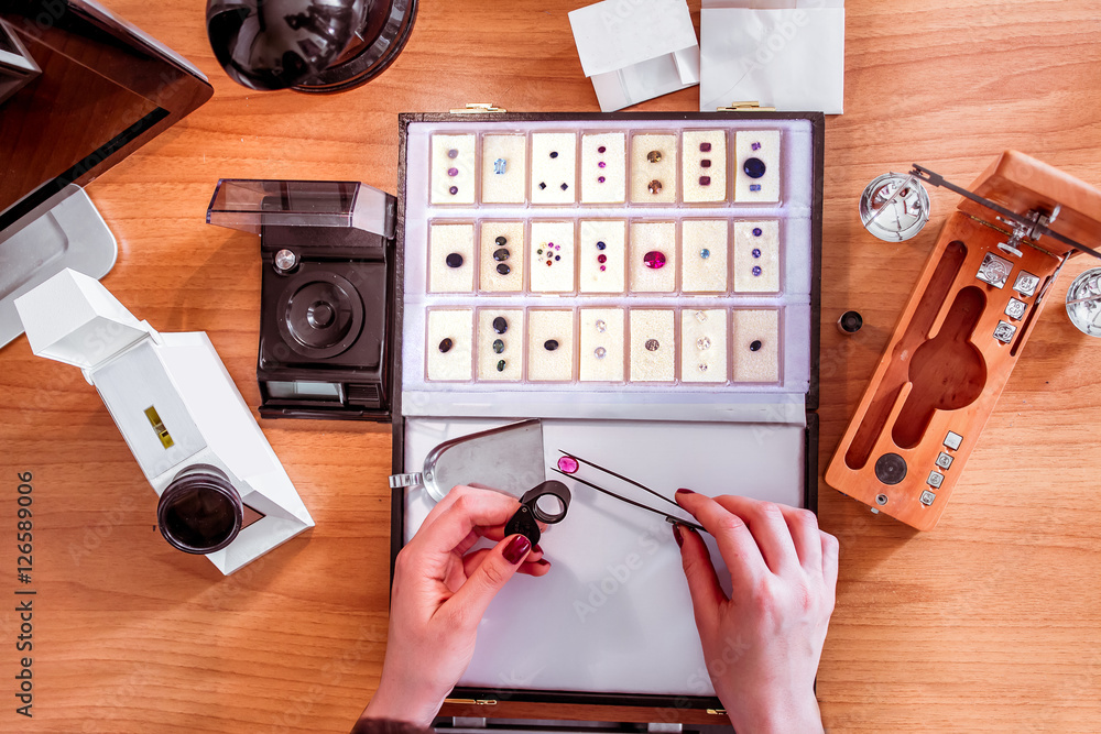 a gemologist examines a ruby using tweezers and evaluating gemstones ...