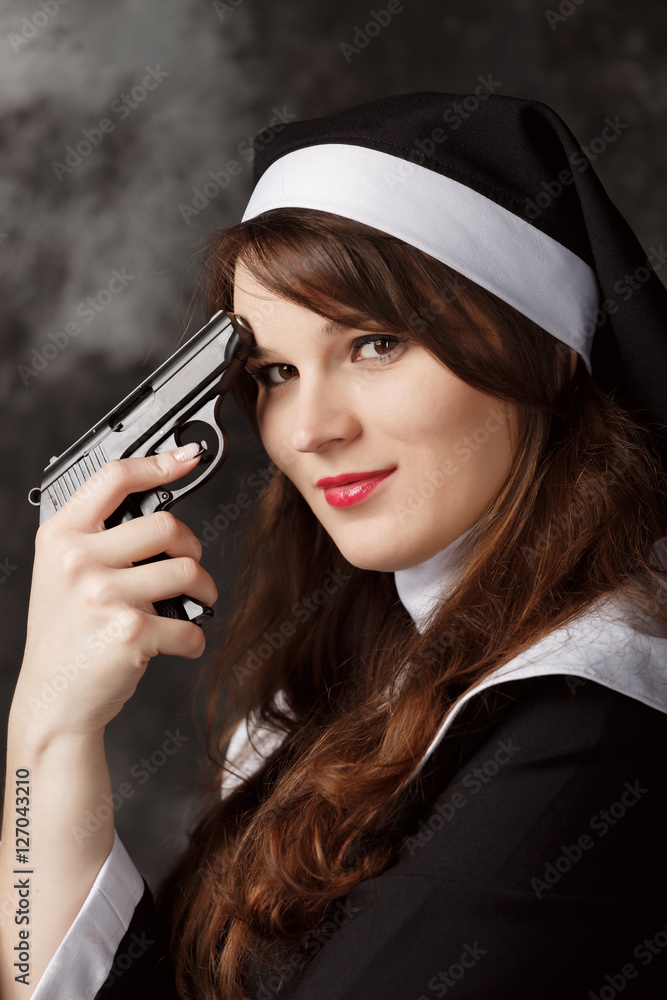 attractive nun with a gun in his hand on a dark background.portrait of ...